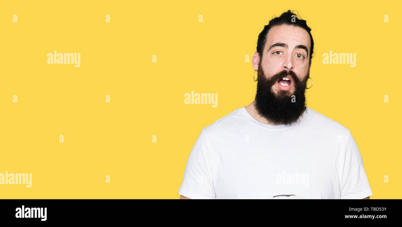 Young man with long hair and bear holding soccer football ball scared ...