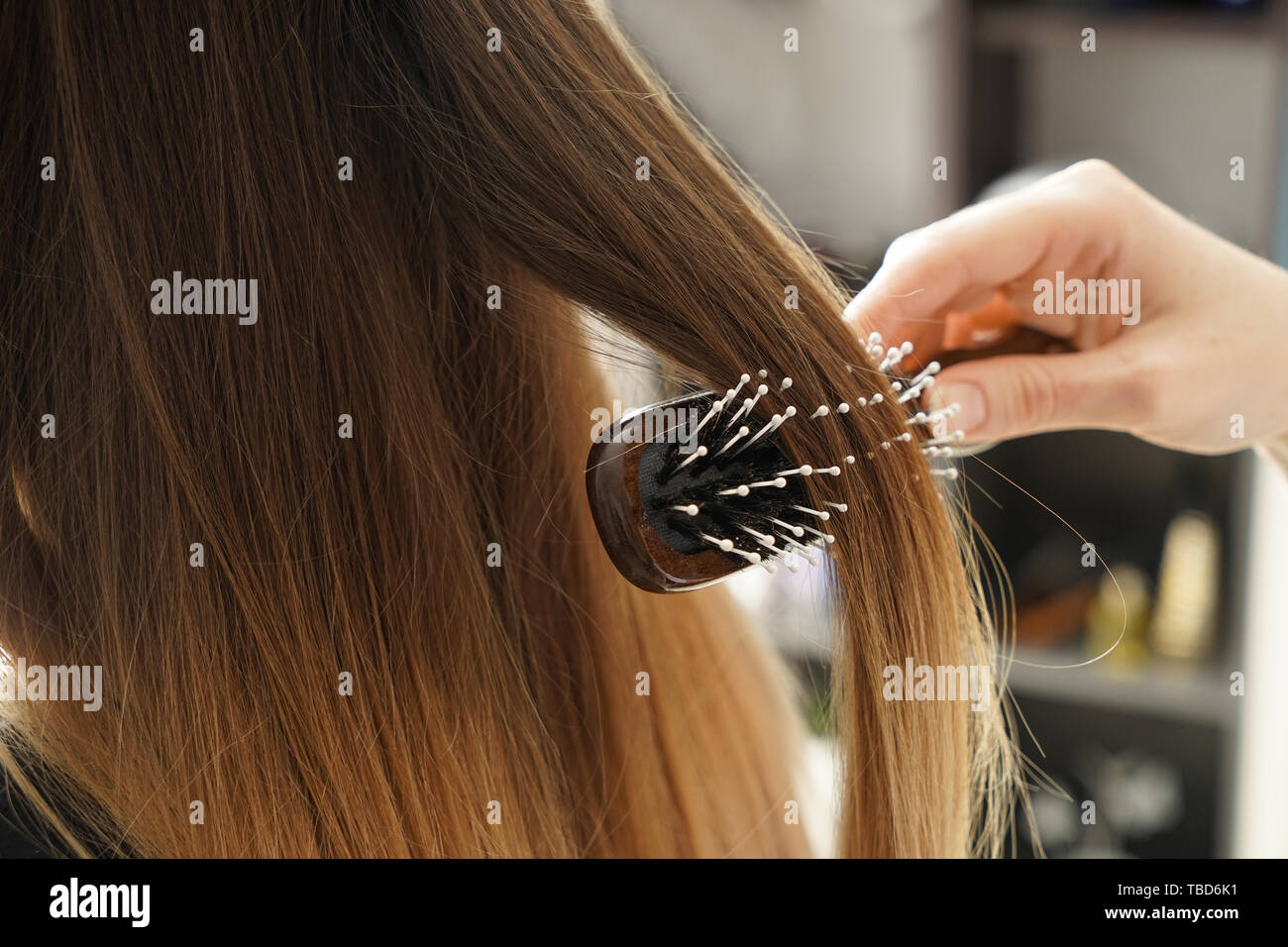 Hairdresser brushing long hair of young woman in salon Stock Photo - Alamy
