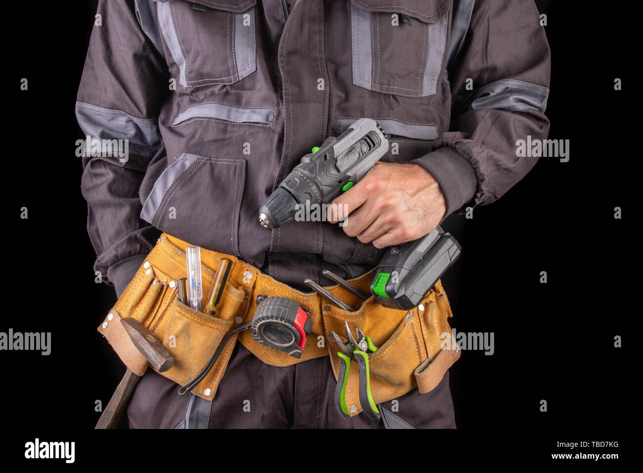 Workman in work clothes and tool belt. Production worker with a drill ...