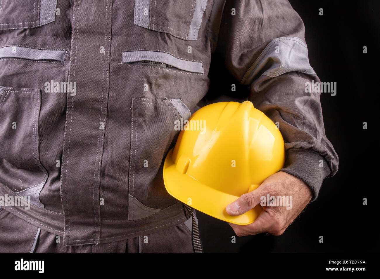 A production worker in workwear with a protective helmet in his hand ...