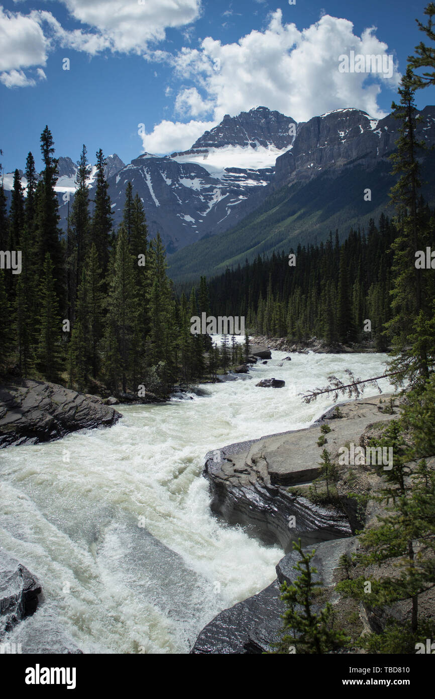 Whitewater rushes around rocks in river in Canadian Rocky Mountains ...