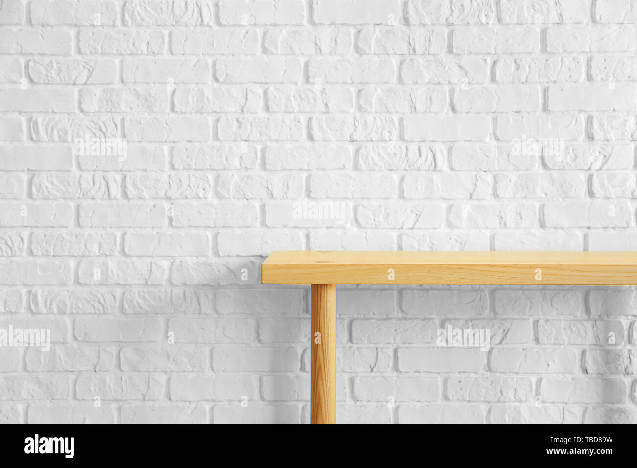 Table near white brick wall Stock Photo - Alamy