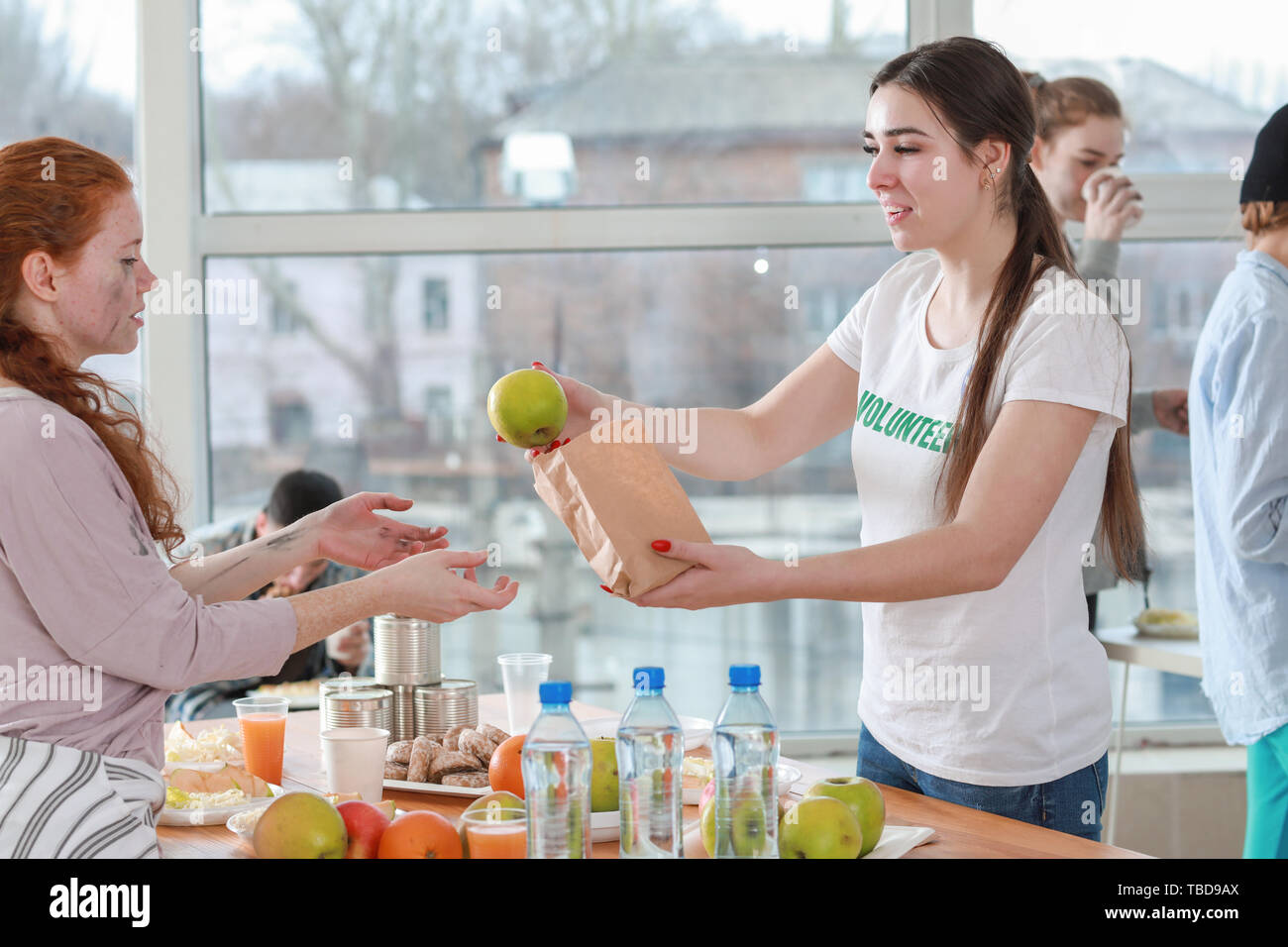 Young volunteers giving food to poor people Stock Photo - Alamy