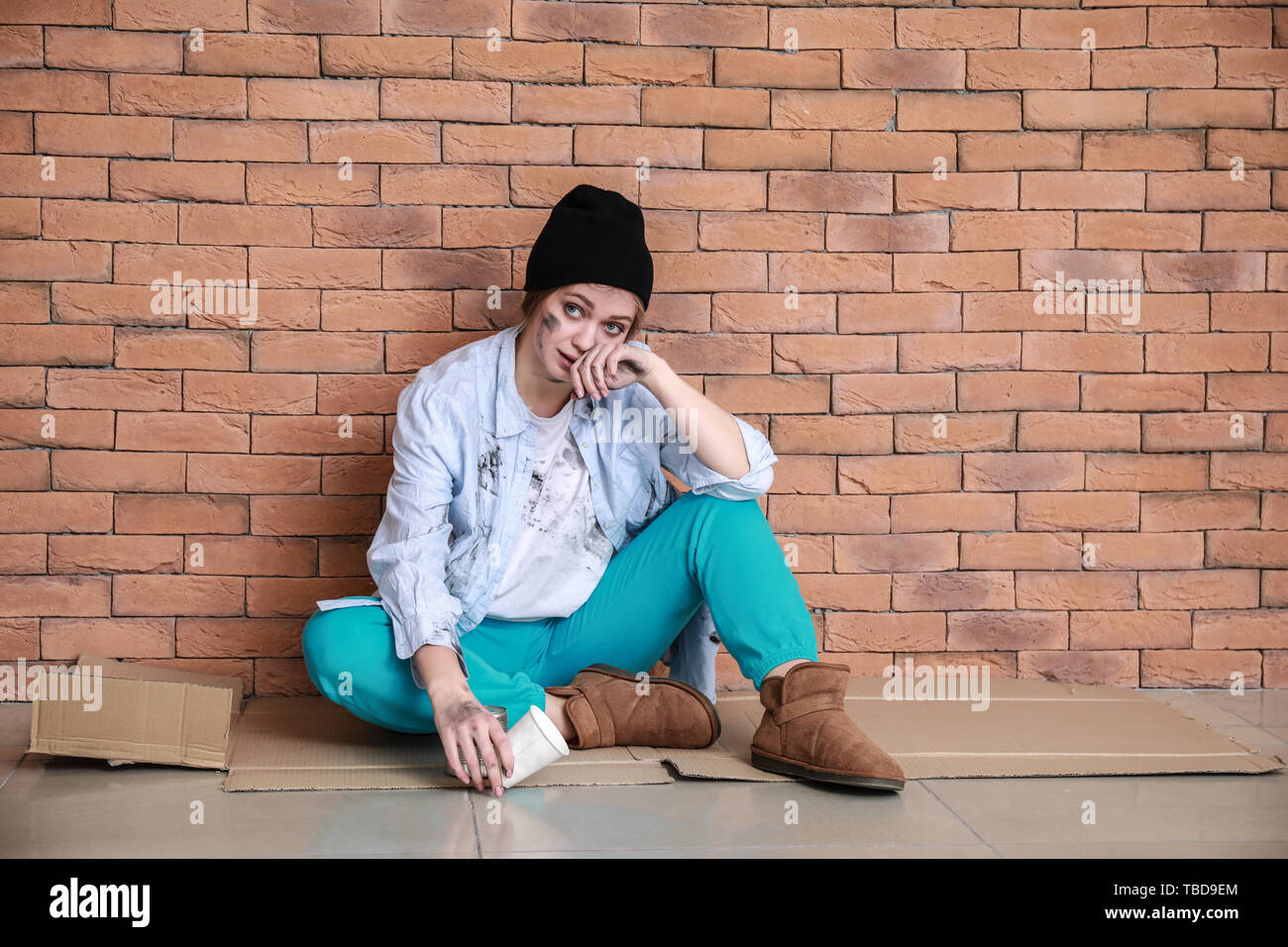 Poor homeless woman sitting near brick wall Stock Photo - Alamy