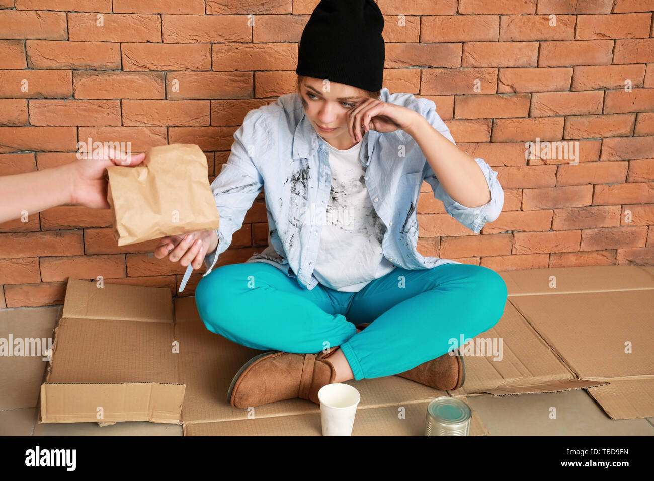 Volunteer giving food to poor woman sitting near brick wall Stock Photo ...