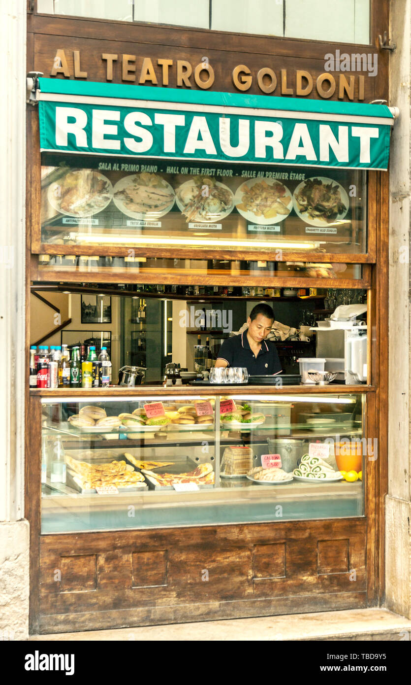 Fast food restaurant showcase with a waiter who prepares food inside ...