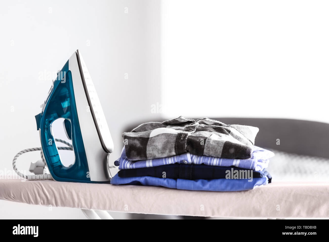 Iron with clean clothes on board Stock Photo - Alamy