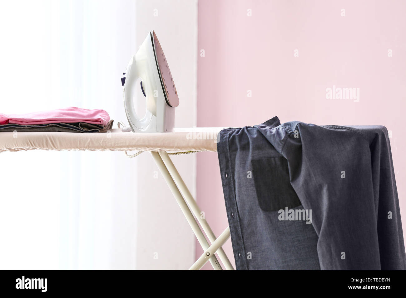 Iron with clean clothes on board Stock Photo - Alamy