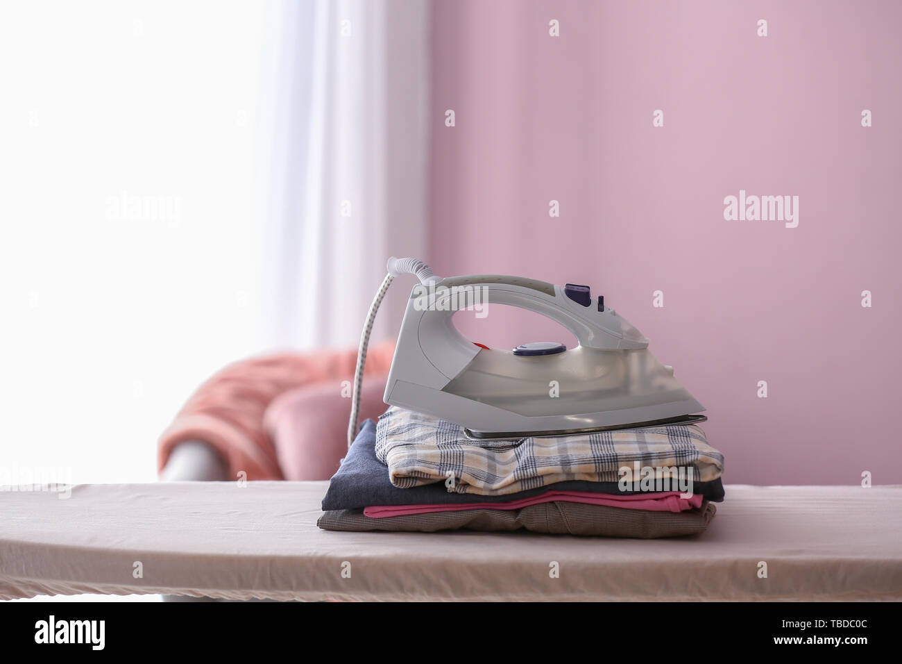 Iron with clean clothes on board Stock Photo - Alamy