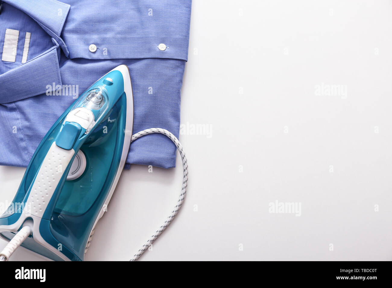 Iron with clean clothes on white background Stock Photo - Alamy