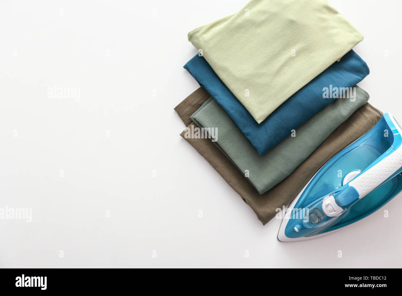 Iron with clean clothes on white background Stock Photo - Alamy