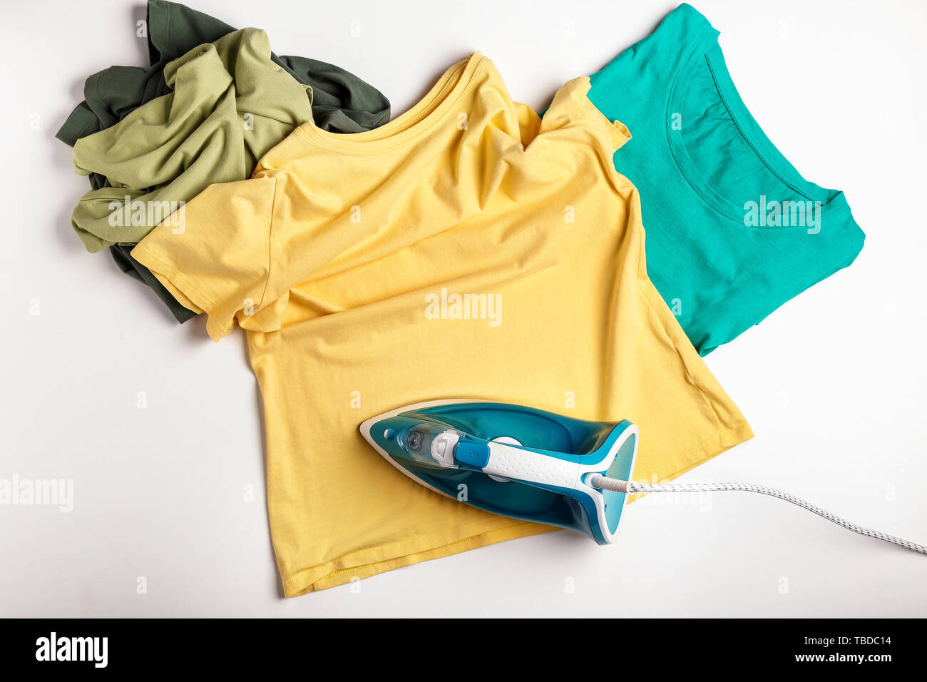 Iron with clean clothes on white background Stock Photo - Alamy