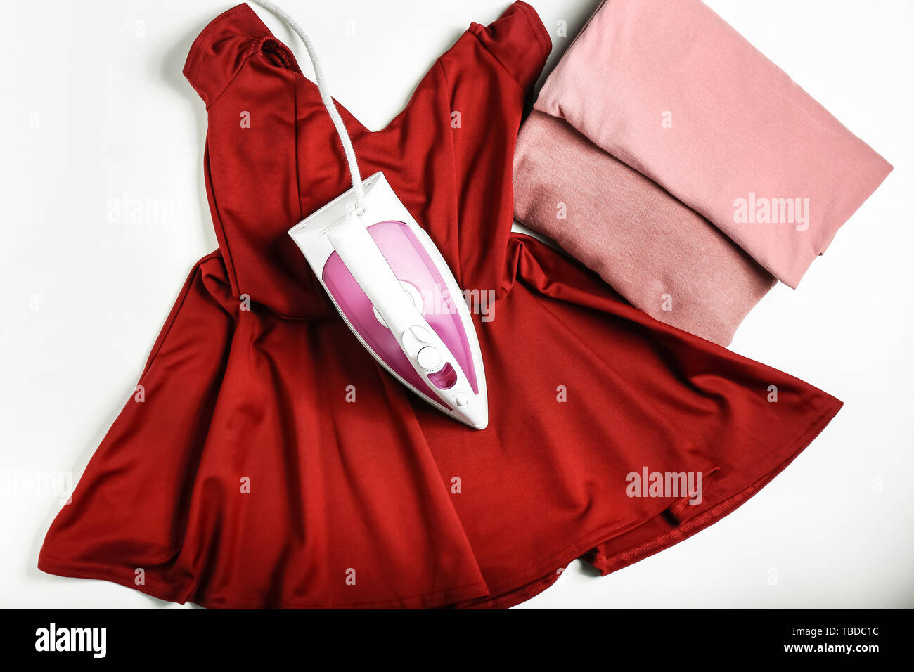 Iron with clean clothes on white background Stock Photo - Alamy