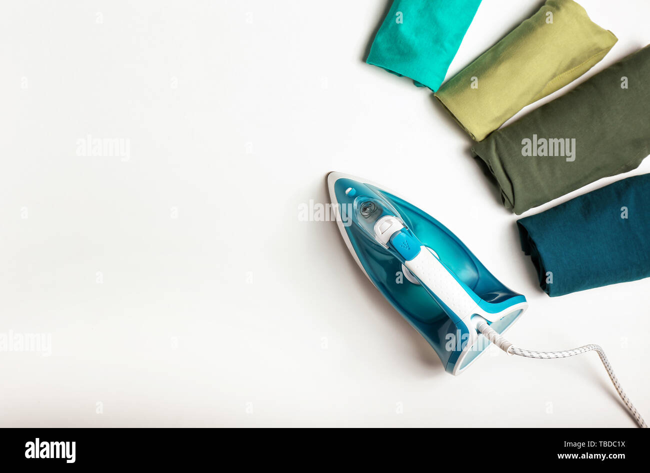 Iron with clean clothes on white background Stock Photo - Alamy