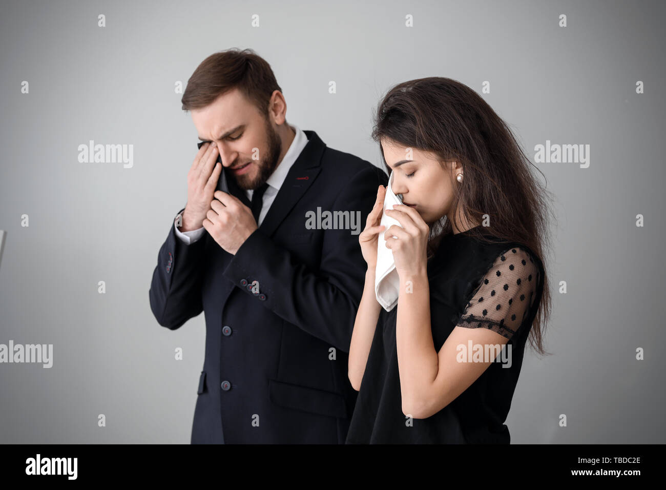 Couple pining after their relative on light background Stock Photo - Alamy