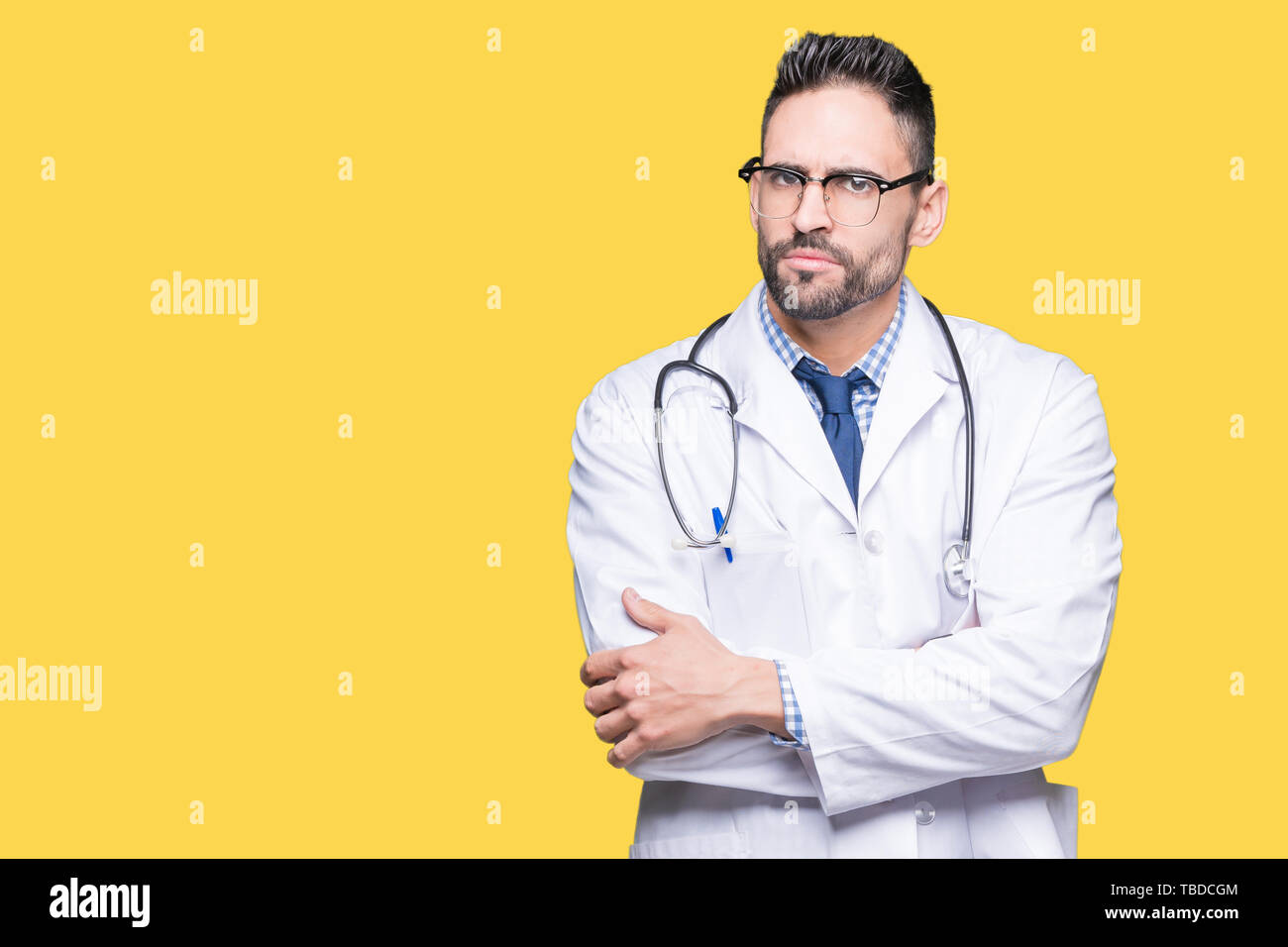 Handsome young doctor man over isolated background skeptic and nervous ...