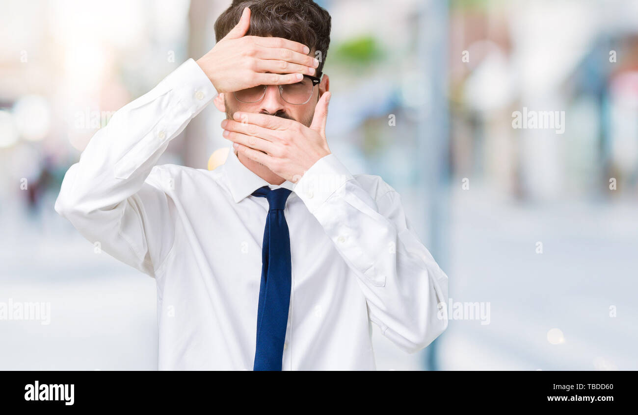 Young handsome business man wearing glasses over isolated background Covering eyes and mouth ...