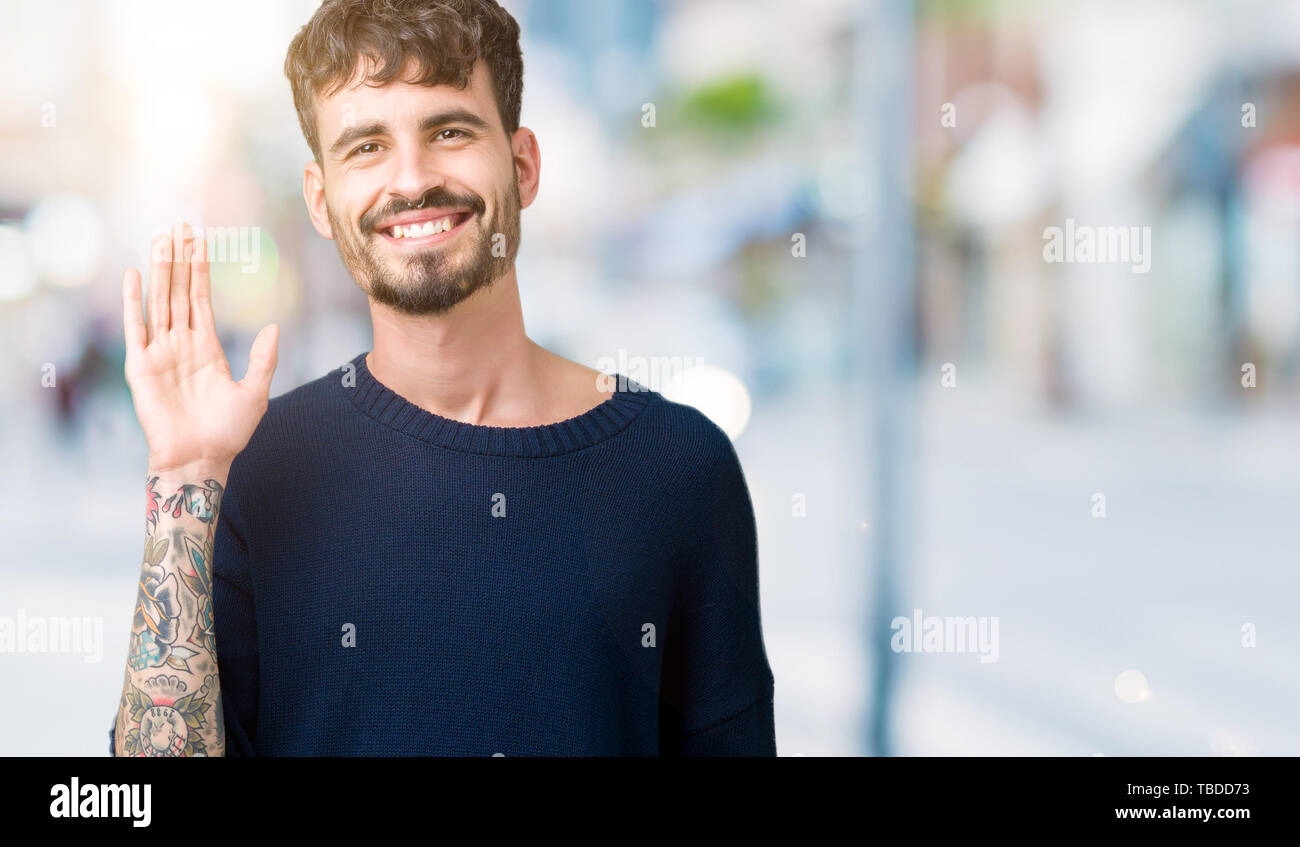 Young handsome man over isolated background Waiving saying hello happy ...