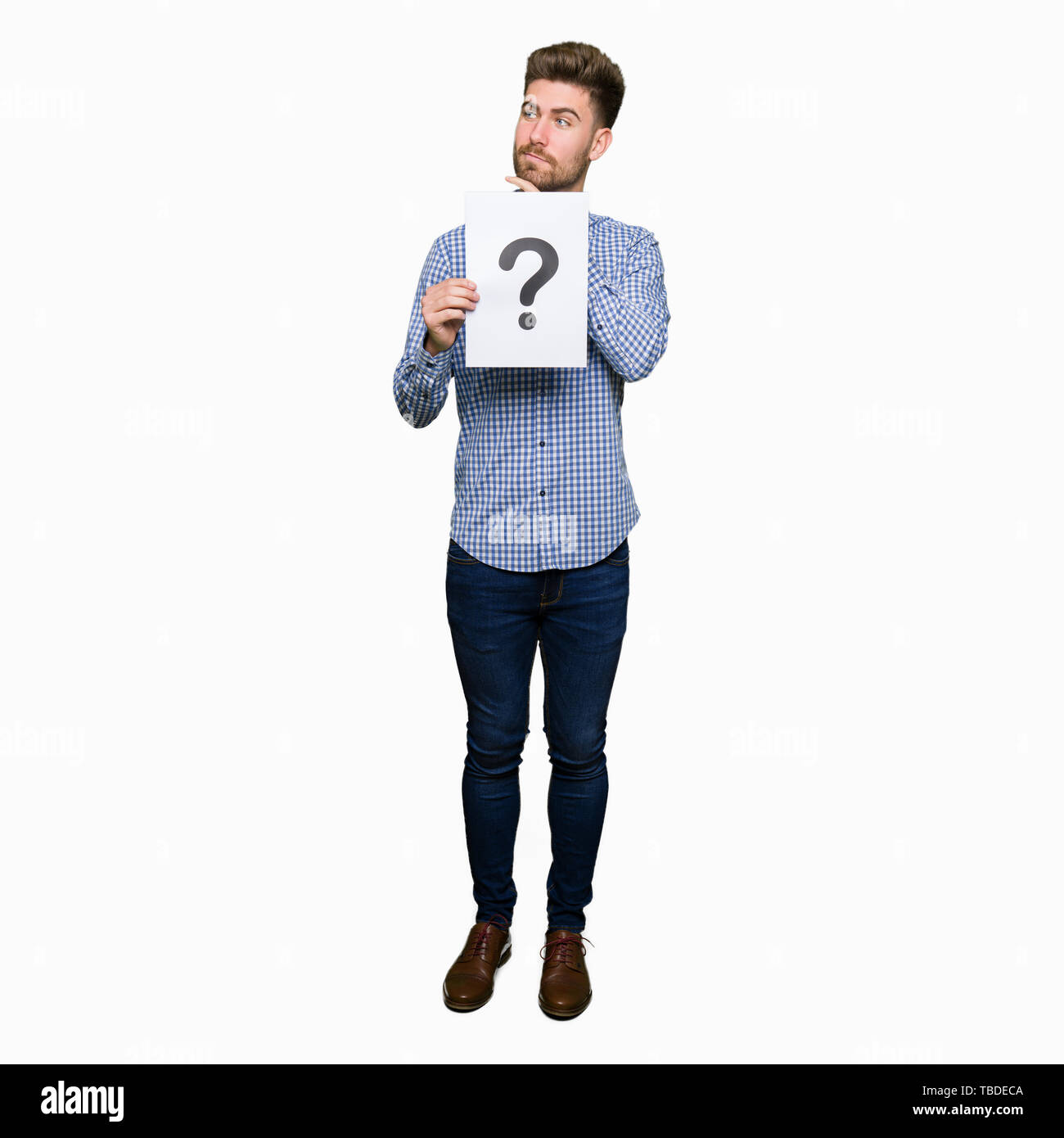 Young handsome man holding paper with question mark serious face ...