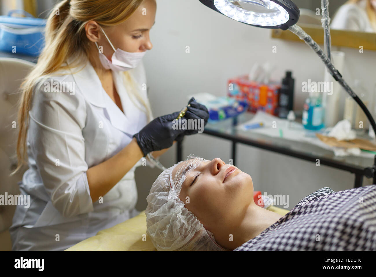 Microblading eyebrows work flow in a beauty salon. Woman having her eye ...