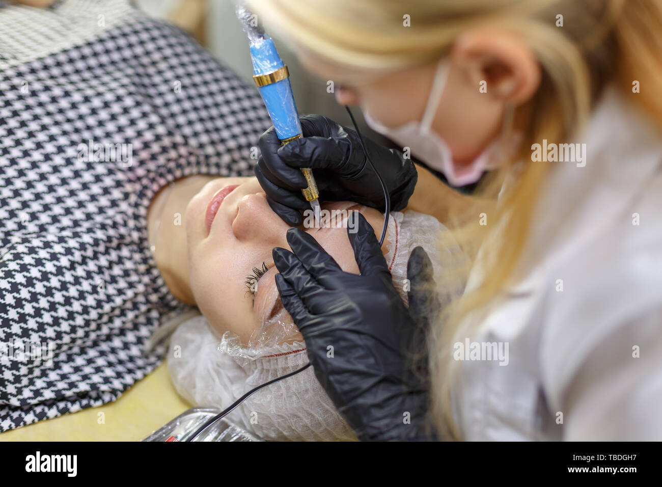 Microblading eyebrows work flow in a beauty salon. Woman having her eye ...