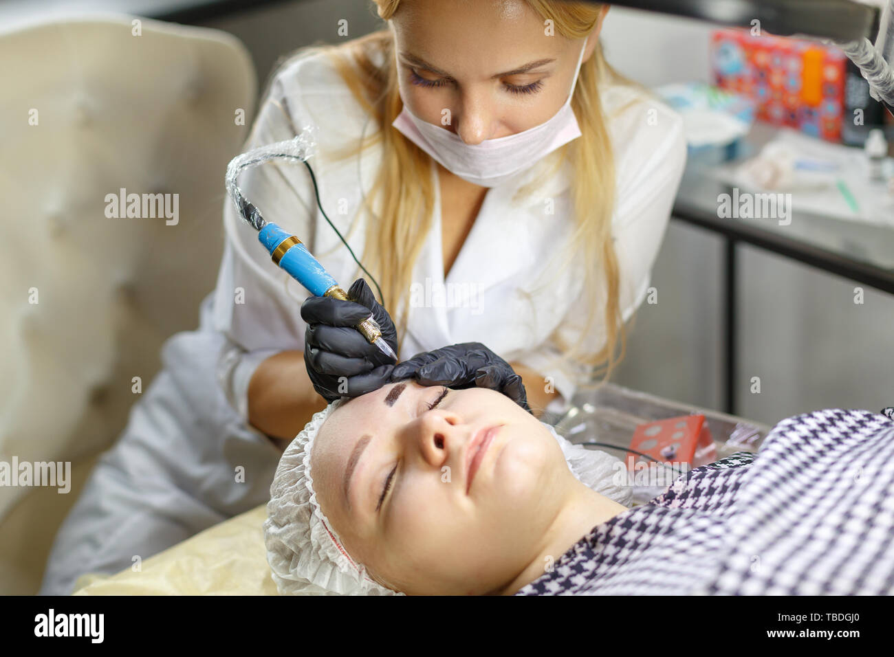 Microblading eyebrows work flow in a beauty salon. Woman having her eye ...