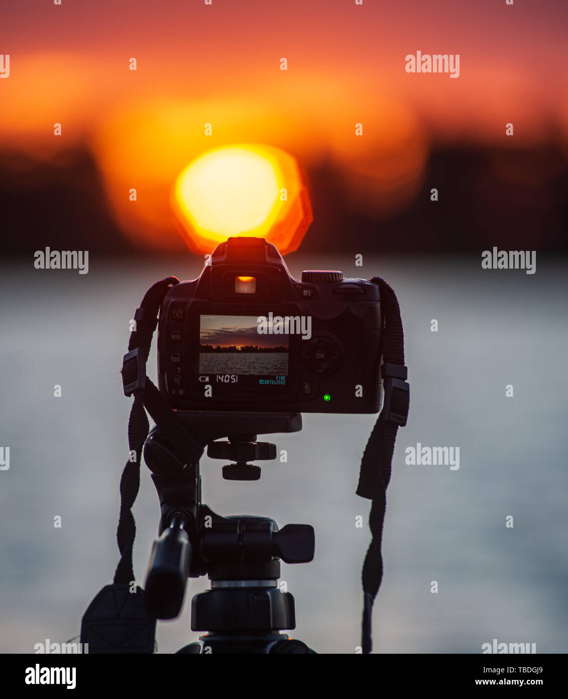 digital camera on a tripod taking pictures of sunset over the lake ...