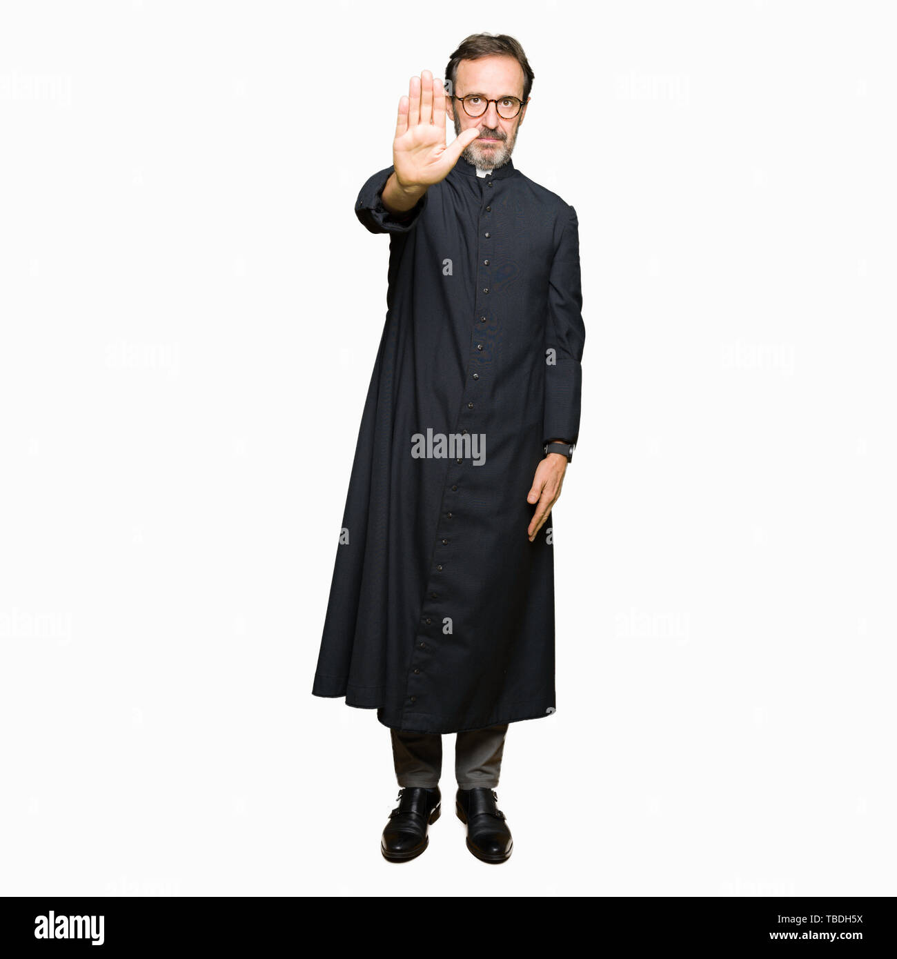 Middle age priest man wearing catholic robe doing stop sing with palm ...