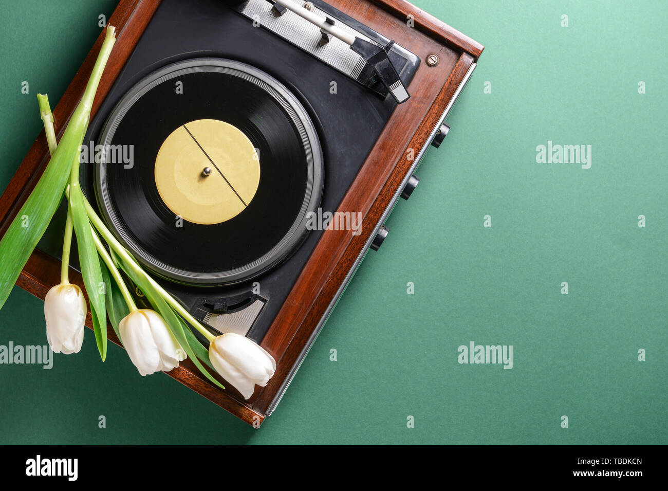 Record player with vinyl disc and flowers on color background Stock ...