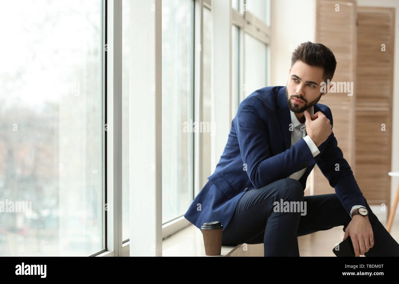 Fashionable young man sitting on window sill Stock Photo - Alamy