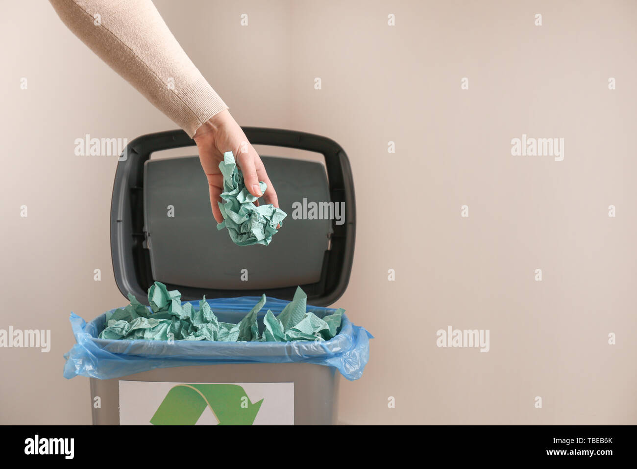 Woman throwing garbage into trash bin on light background. Recycling ...