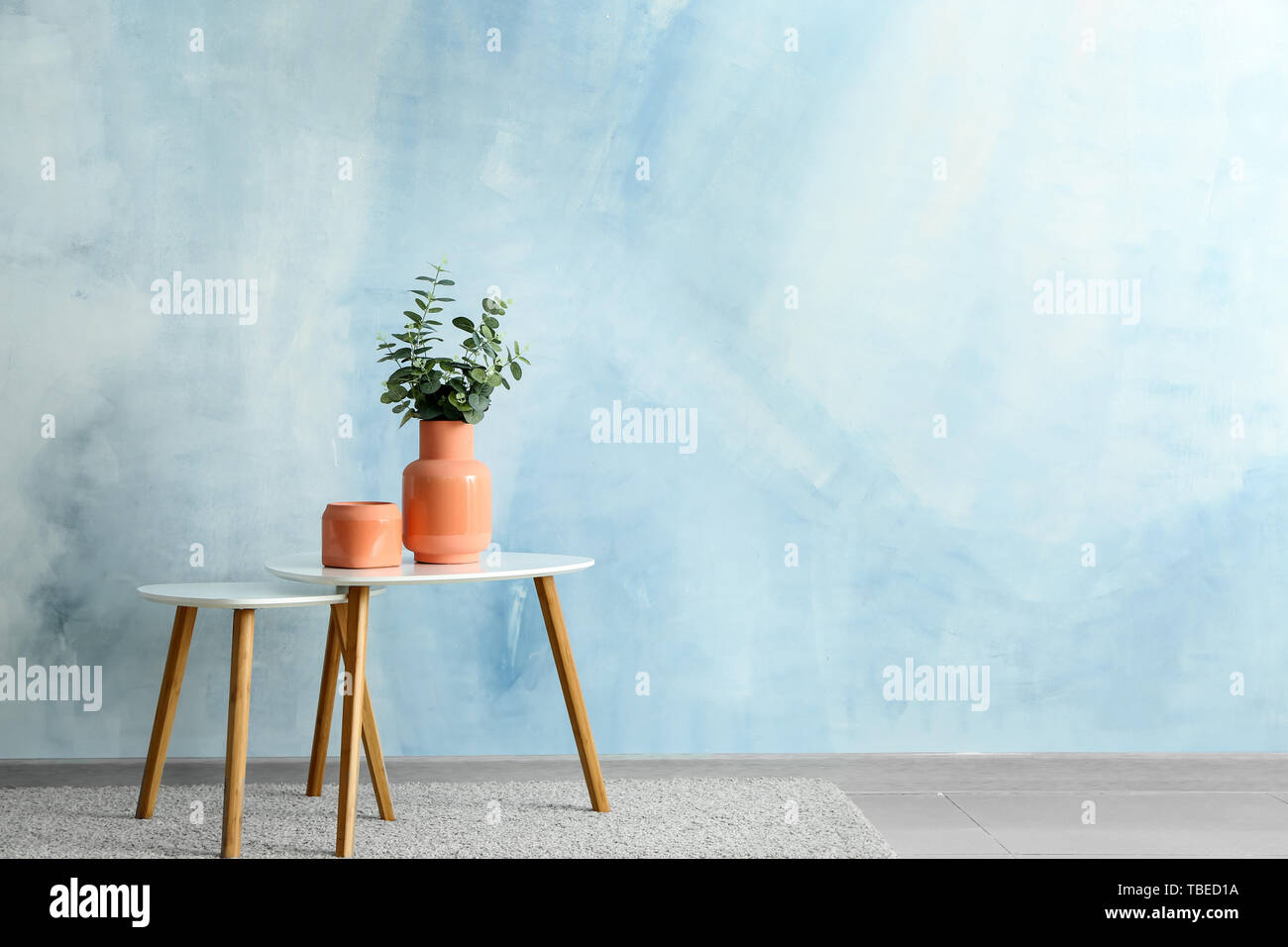 Tables with decor near color wall in room Stock Photo - Alamy