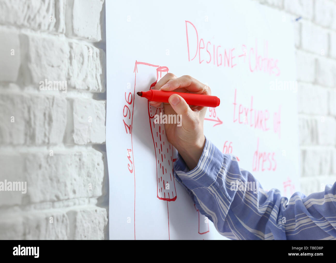 Female fashion designer drawing on big paper sheet in office Stock ...