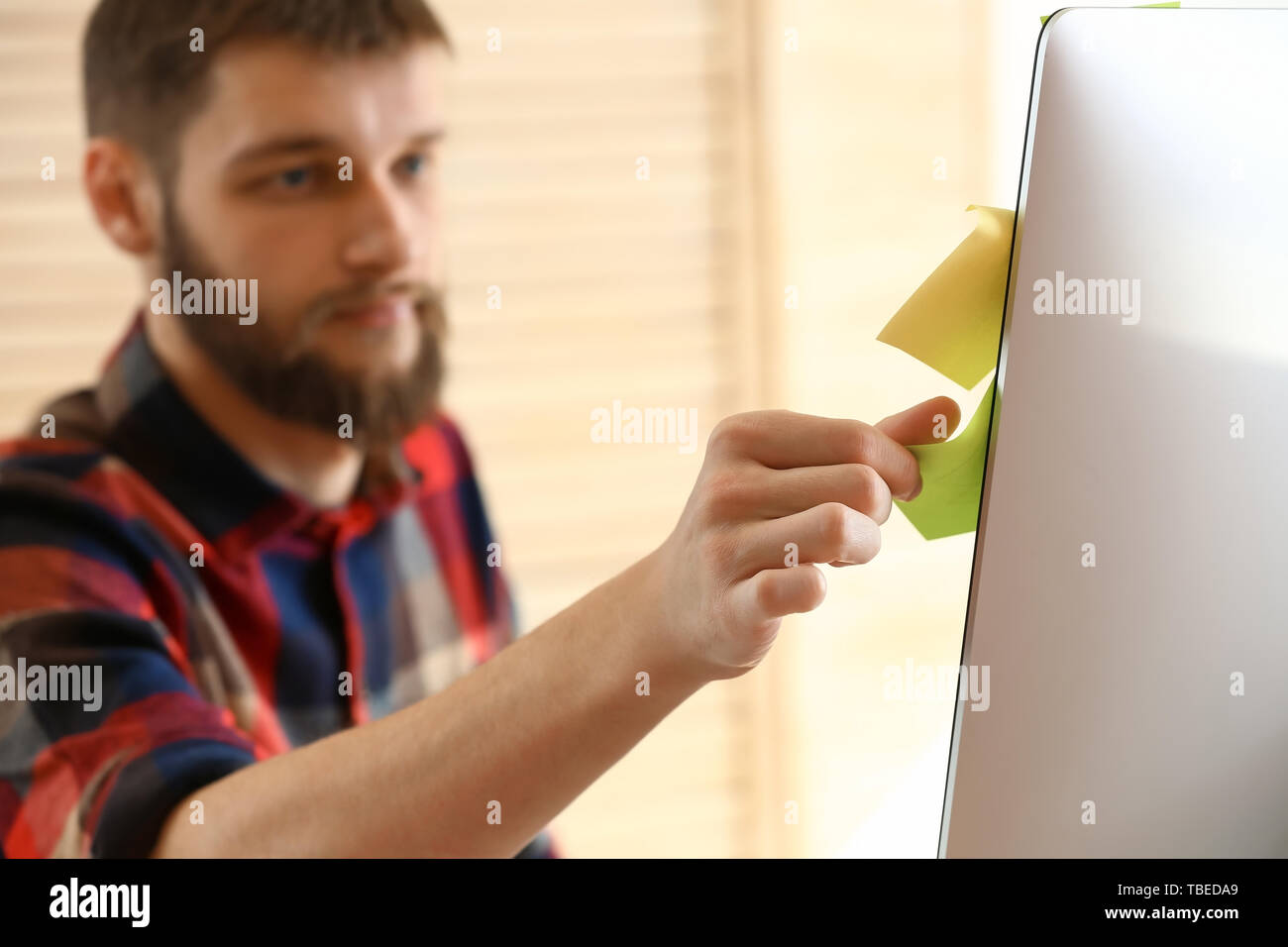Male designer attaching stickers to monitor in office Stock Photo - Alamy