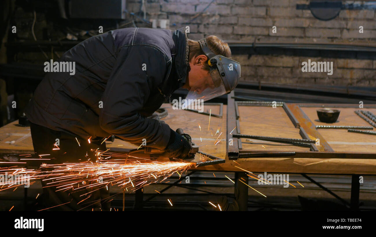 Blacksmith sawing metal with hand circular saw Stock Photo - Alamy