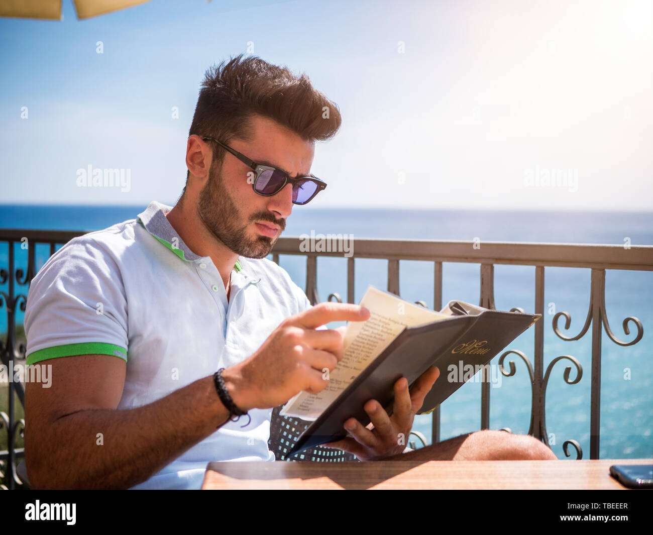 Young man reading menu at outdoor bar Stock Photo - Alamy