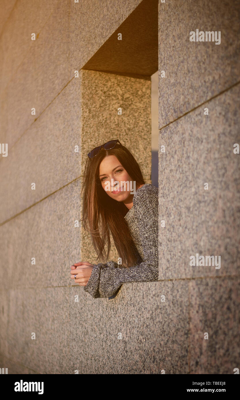 Young woman enjoying the sunlight in a square shaped window made of ...