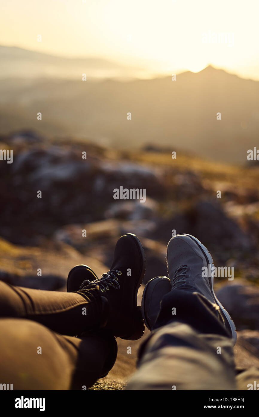 Detail of two pair of feet in front of a defocused landscape at sunset ...
