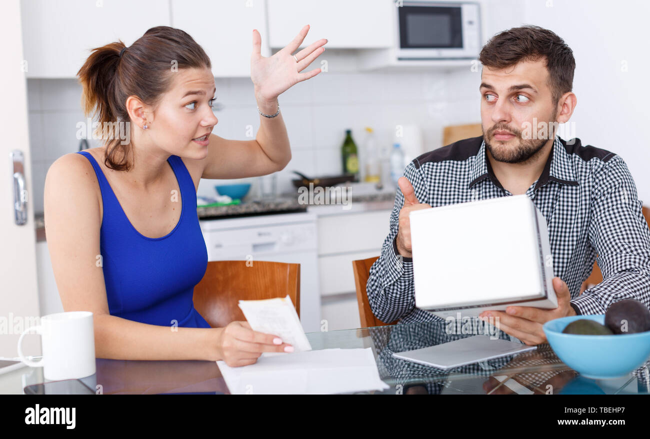Unhappy young woman and man with box of purchase having conflict at ...