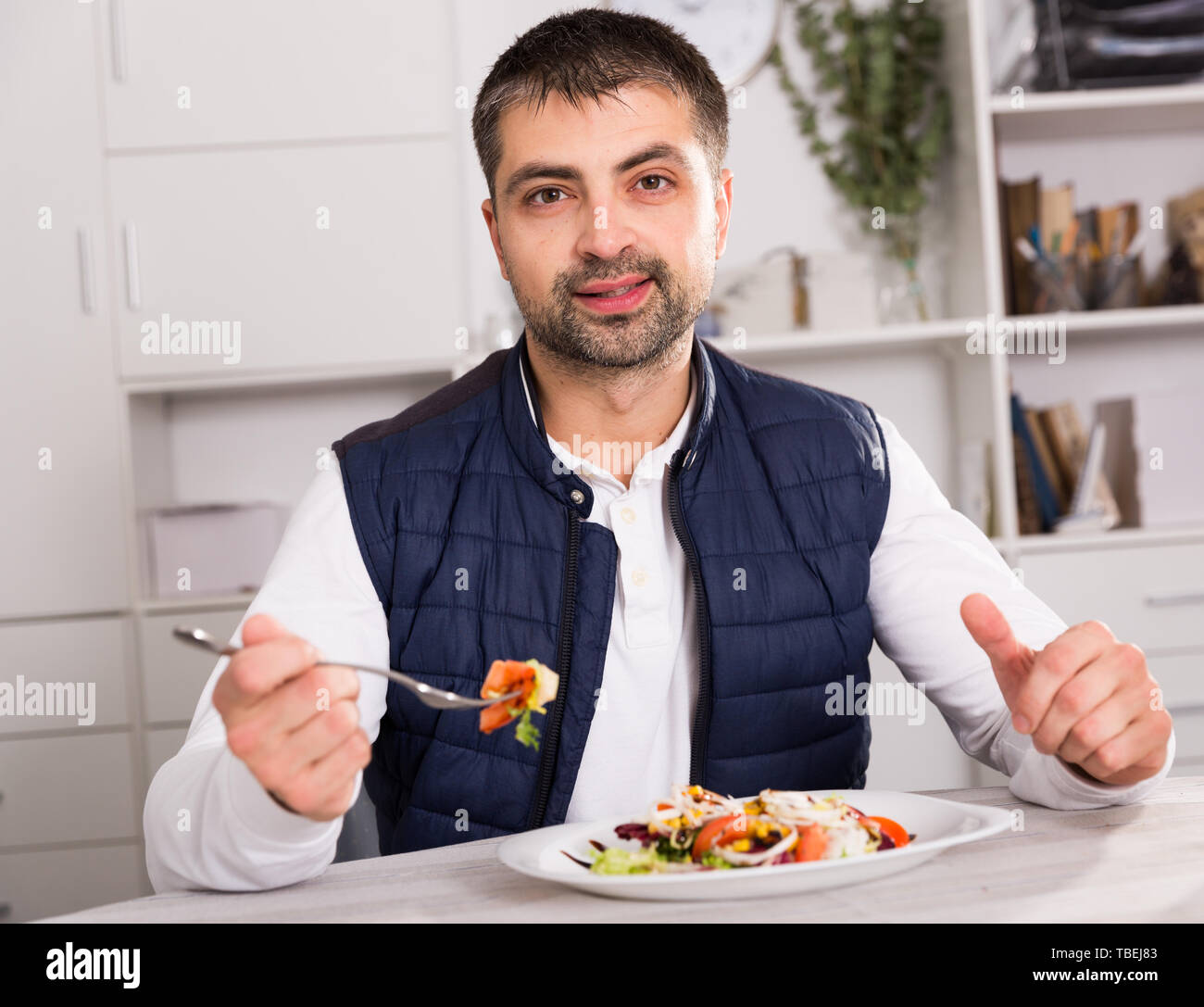 Portrait of young man eating vegetable salad and holding fork Stock ...