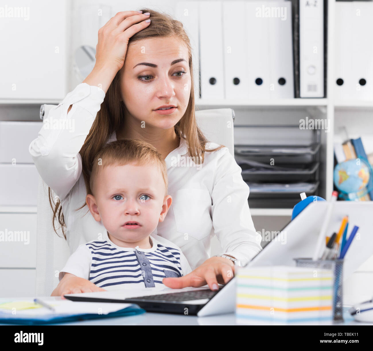 Perplexed girl with kid is having problems while working in office ...