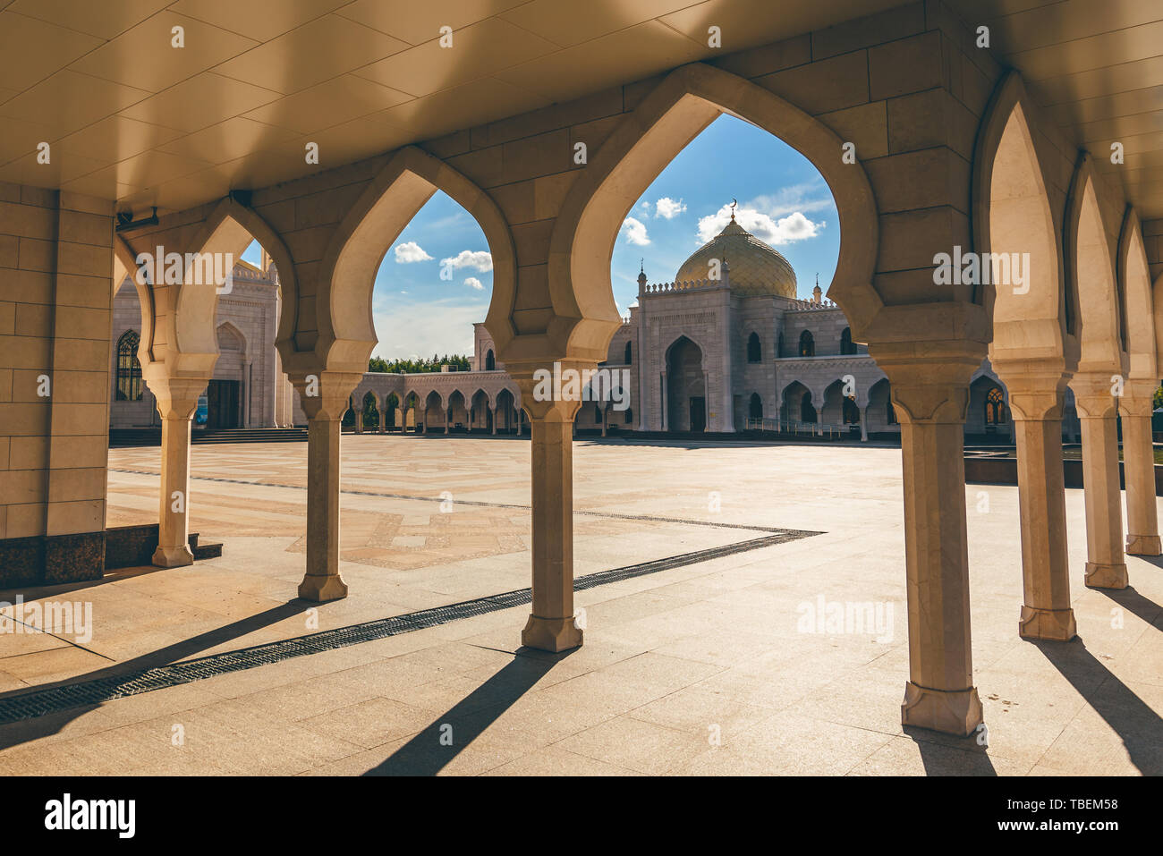 View of the white mosque in the sunset light through the Arches ...
