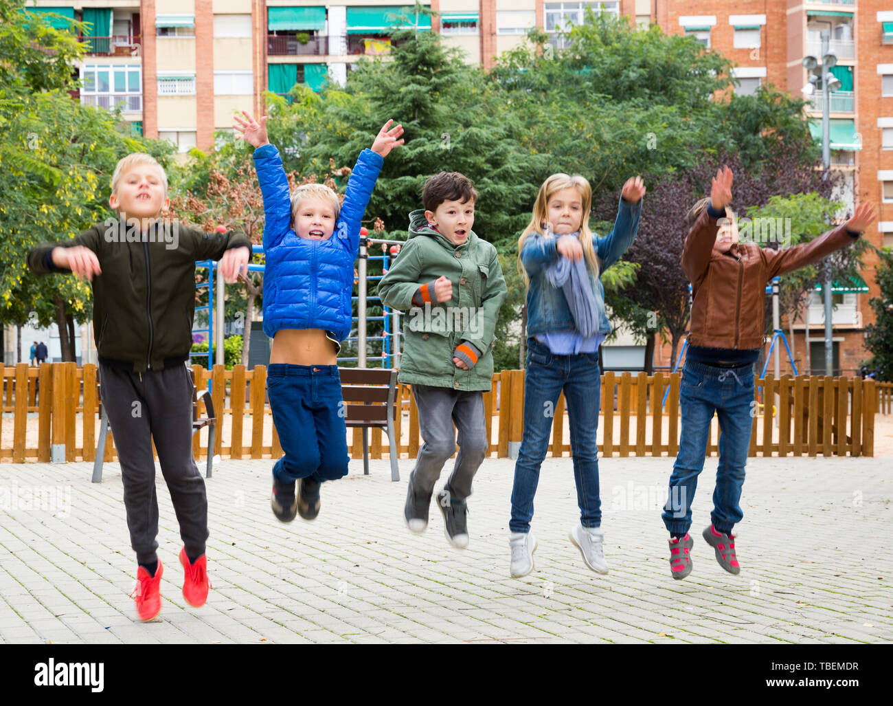 Group of laughing happy children jumping together on playground Stock ...