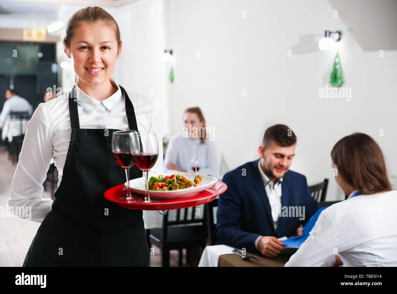 Portrait of welcoming female waiter who is standing in restaurante ...