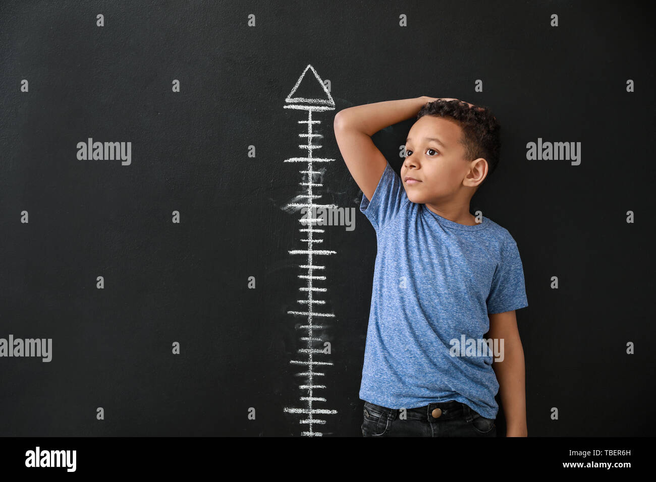 African-American boy measuring height near dark wall Stock Photo - Alamy