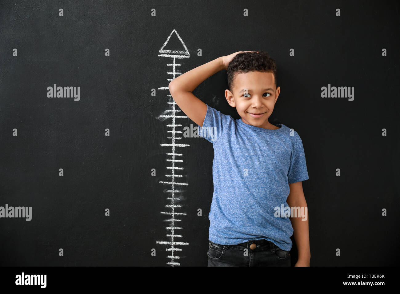 African-American boy measuring height near dark wall Stock Photo - Alamy