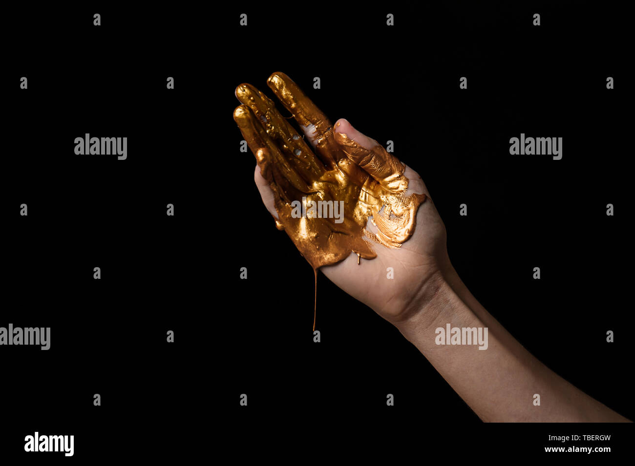 Female hand with golden paint against dark background Stock Photo - Alamy