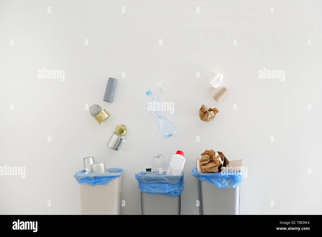 Garbage falling into trash bins on white background Stock Photo - Alamy
