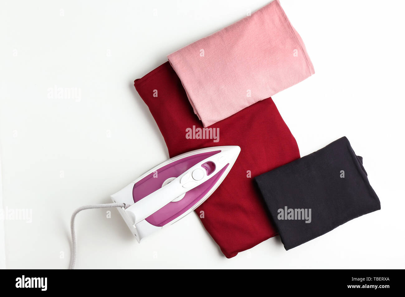 Iron with clean clothes on white background Stock Photo - Alamy