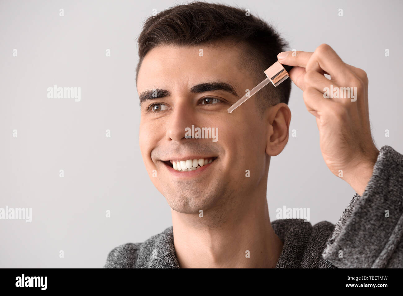 Handsome man applying face serum on light background Stock Photo - Alamy